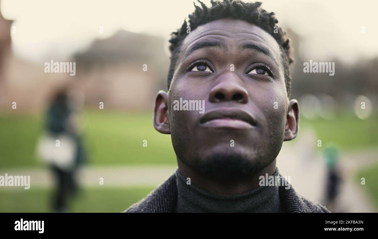 Contemplative young African black man standing looking at sky with HOPE ...