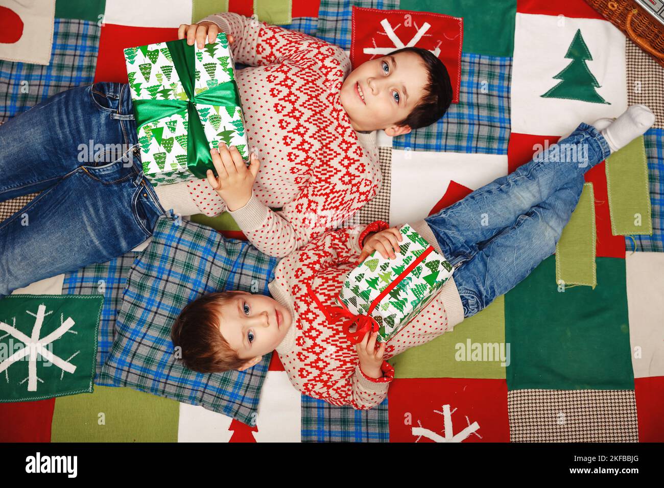 Kids in santa hat lie near christmas gifts and smile. Xmas holiday ...