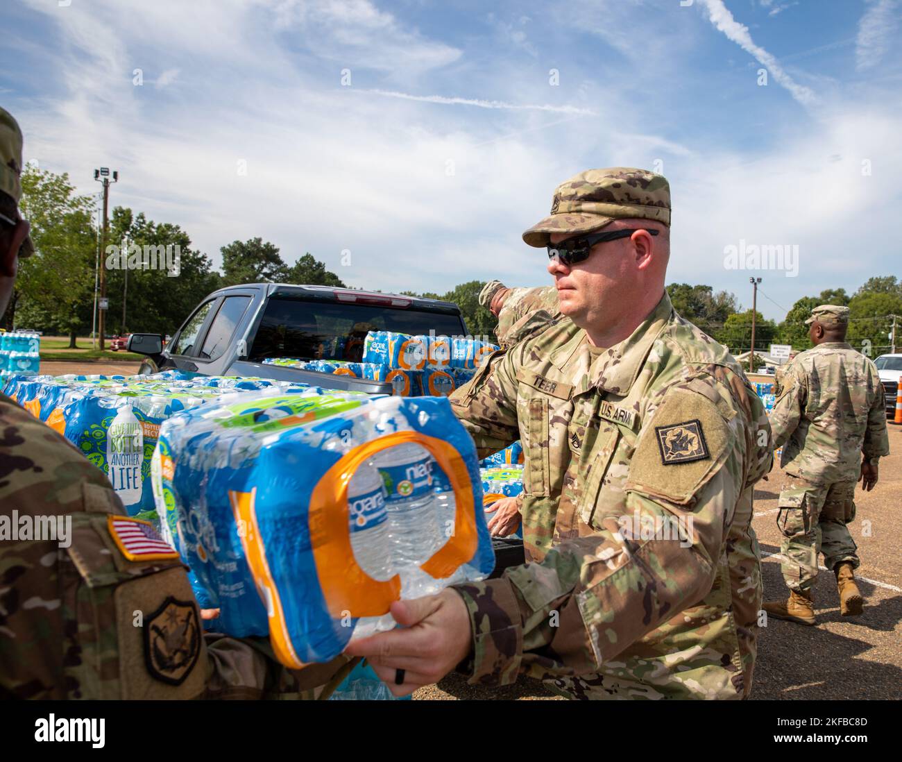 A Mississippi National Guard Soldier passes a case of water to another ...