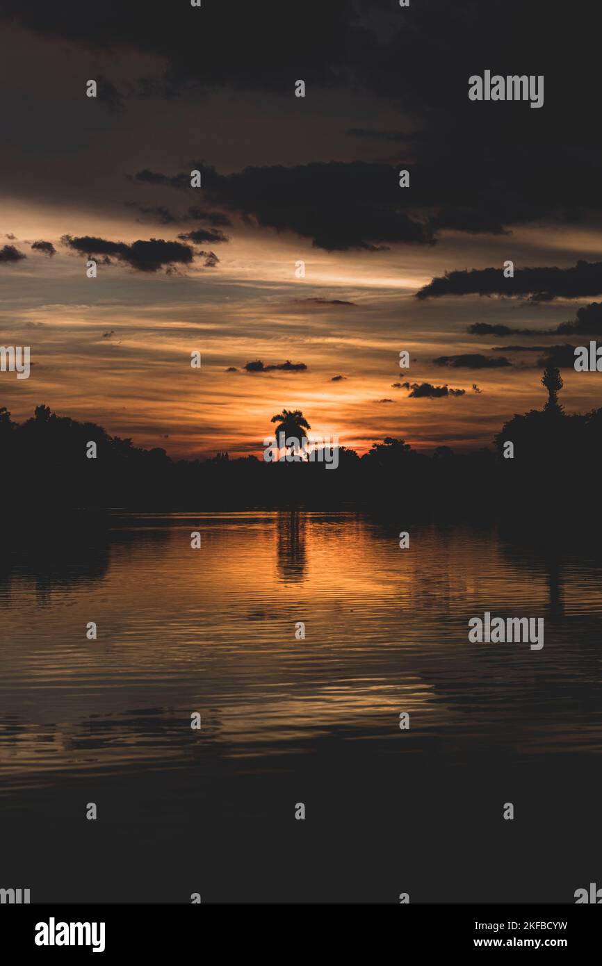A scenic view from the lakeshore of dark orange sunset sky and ...