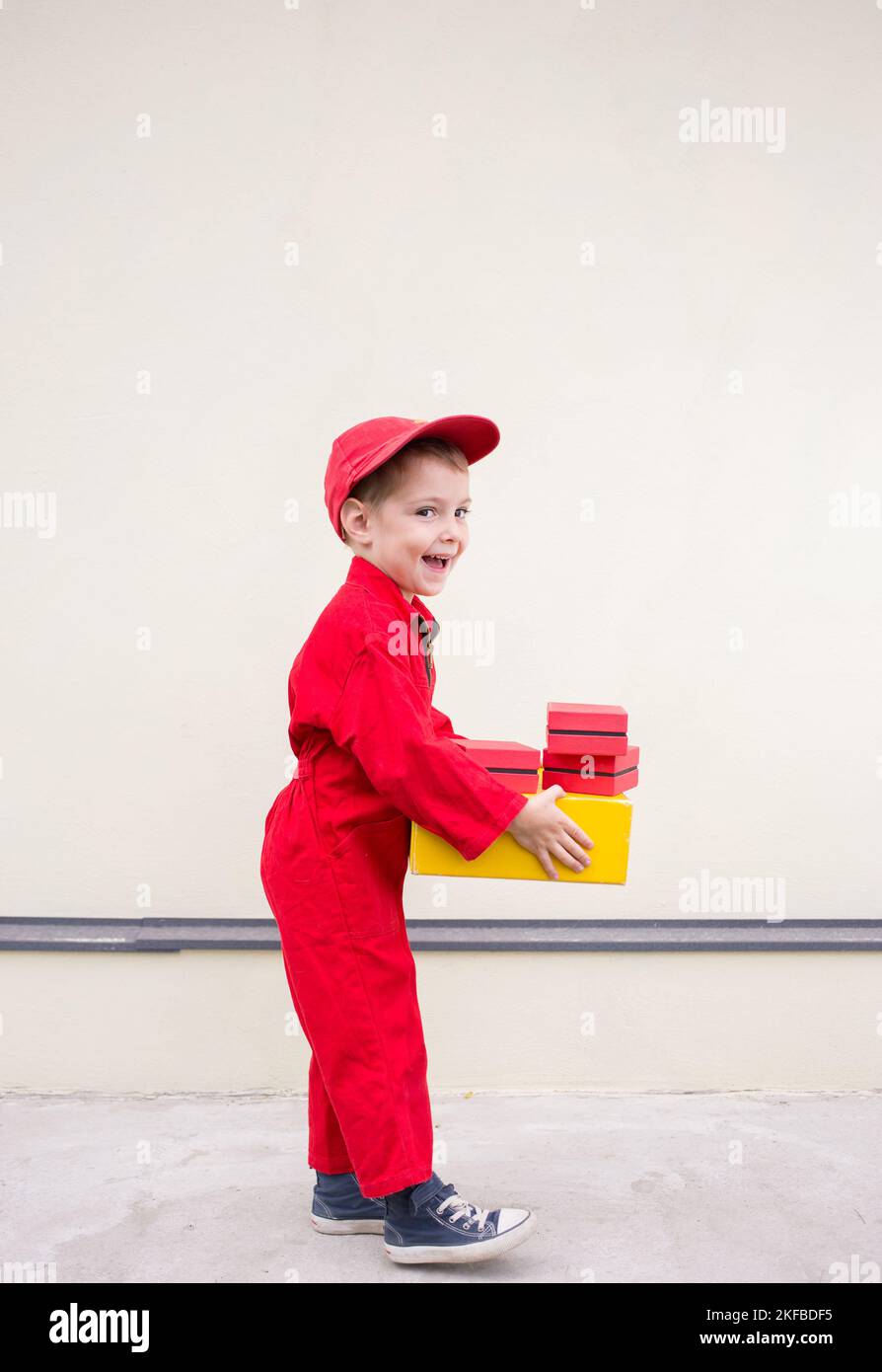 cheerful positive boy 3-4 years old in a red uniform and cap with a ...