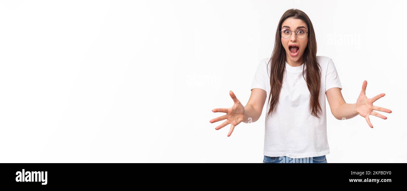 Watch out. Alarmed and shocked, scared pretty girl raising hands to ...