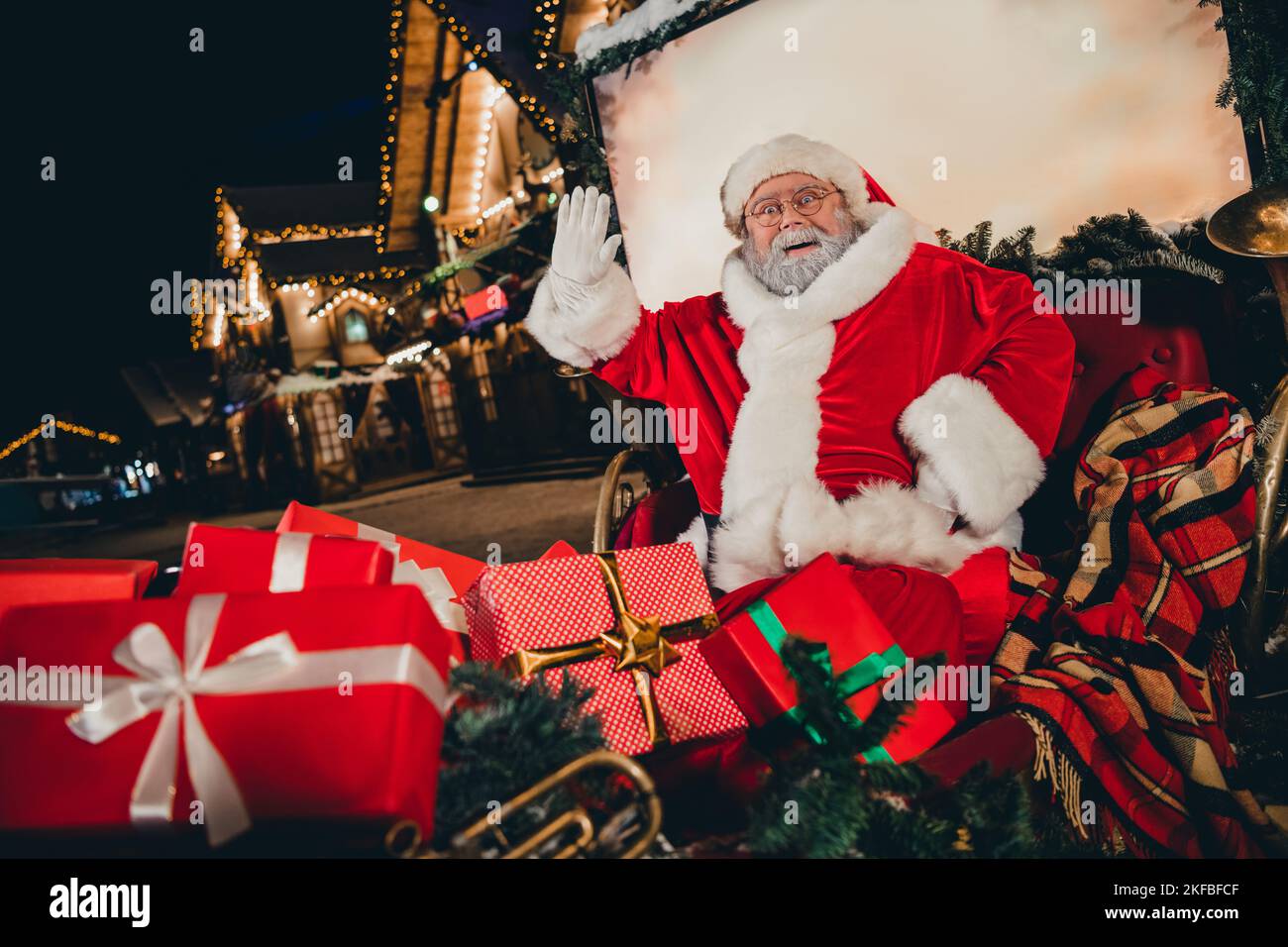 Photo of positive bearded santa claus sit sleigh raise hand wave palm ...