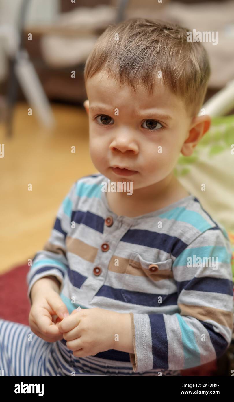 Portrait of a little angry boy sitting in an armchair Stock Photo - Alamy