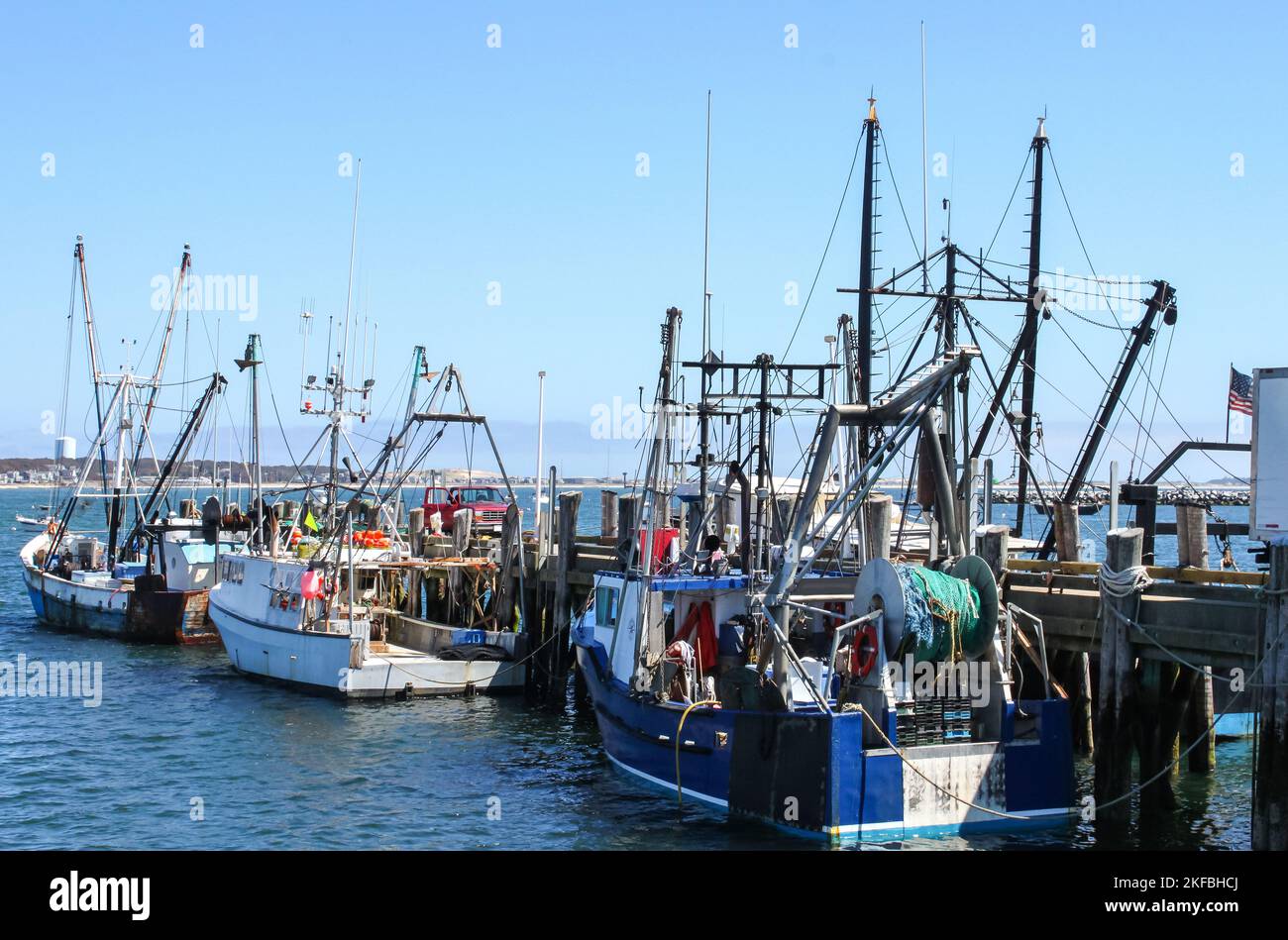 Fishing boats moored at the dock with a pick-up truck with the door ...