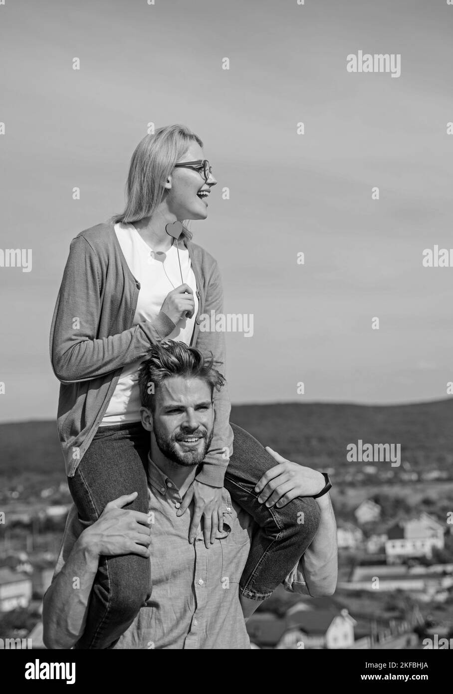 Idyllic date concept. Man carries girlfriend on shoulders, sky ...
