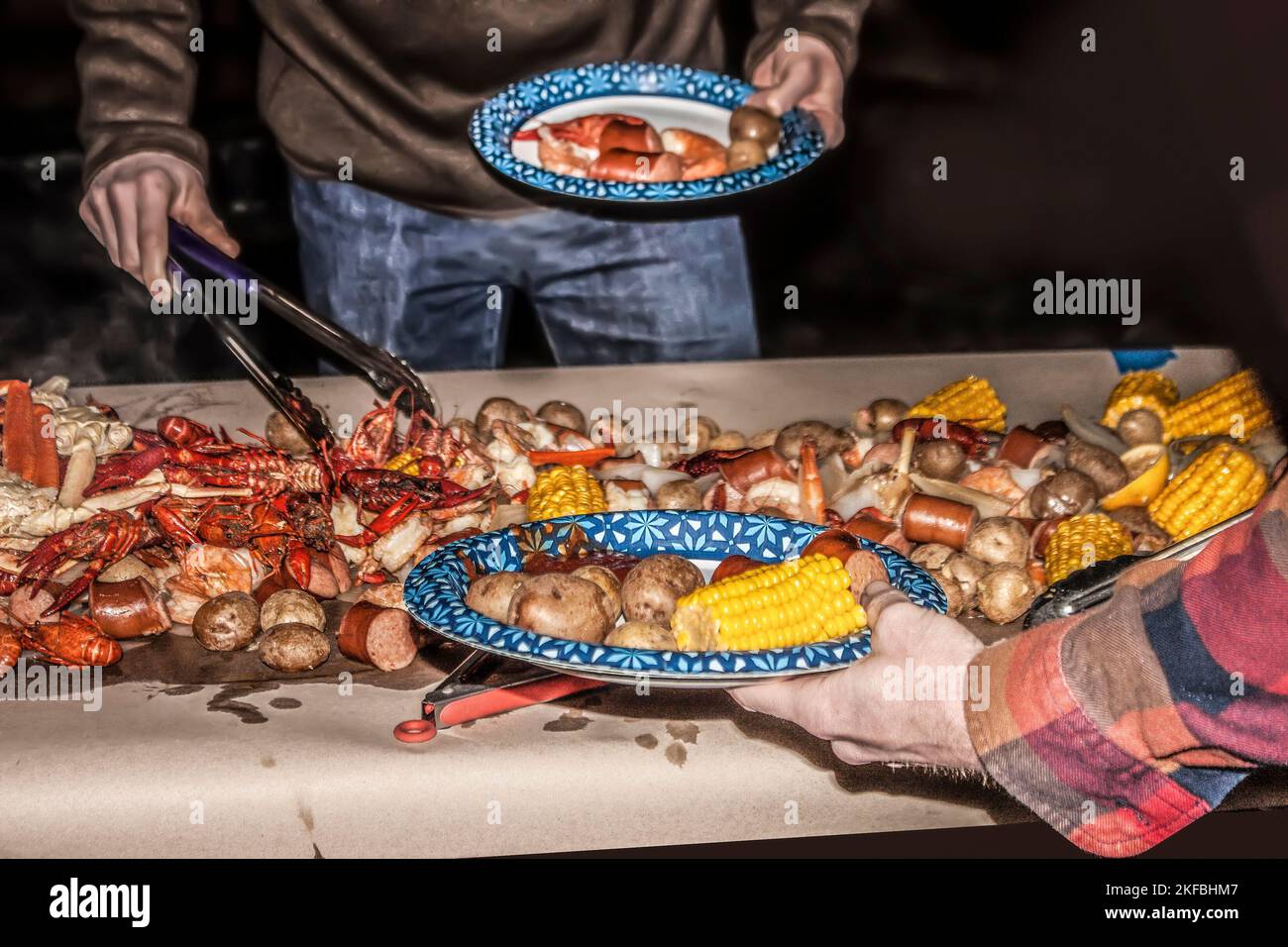 Hand of man holding paper plate as he fills it with food from seafood ...