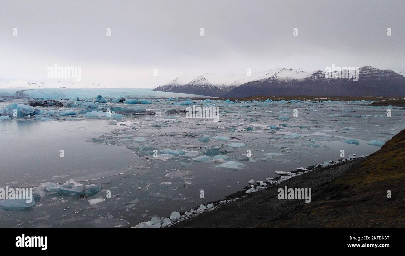 An alluring view of a frozen lake in the winter, with snowy mountain ...