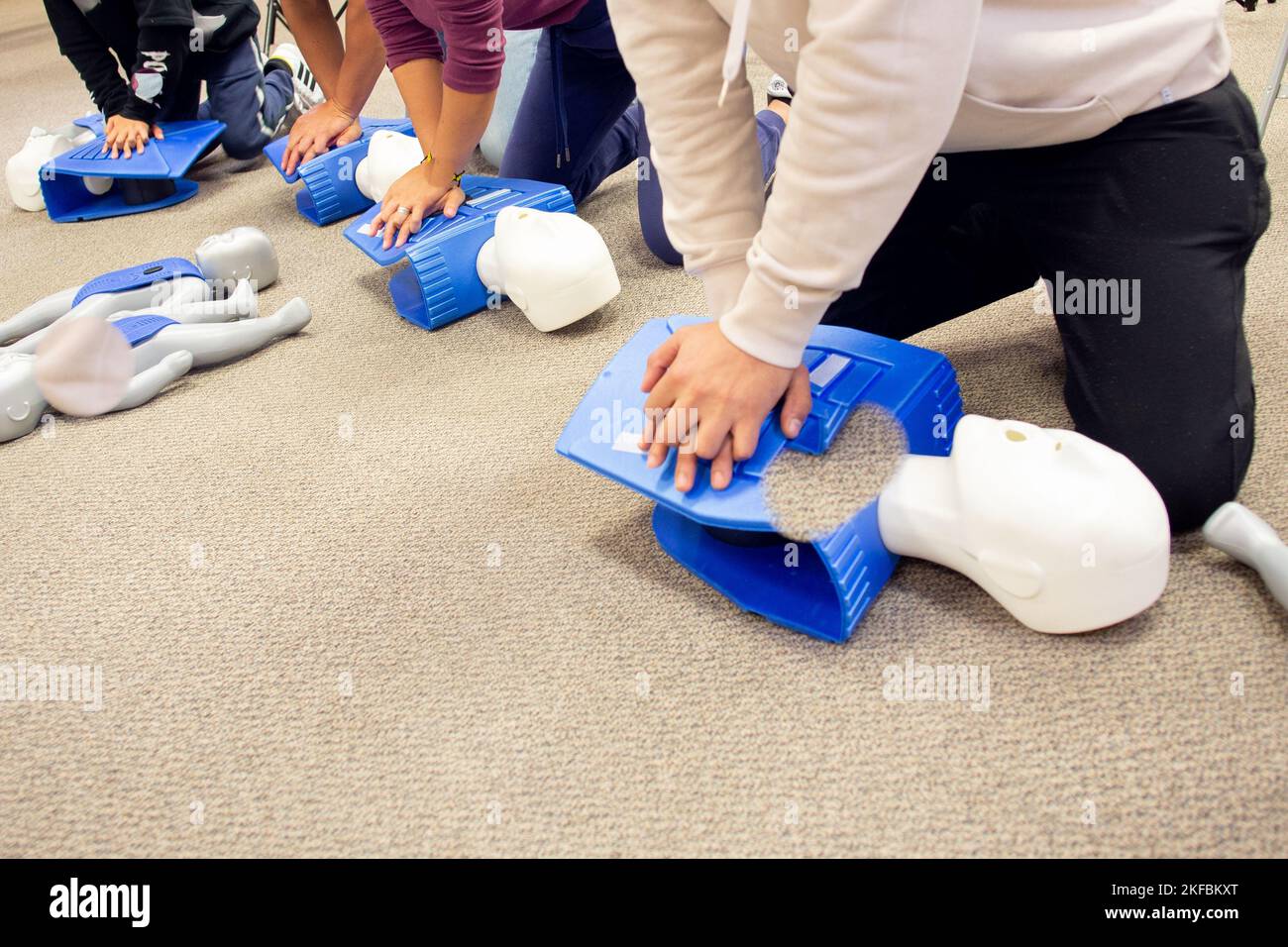 A closeup shot of people learning and practicing CPR on dummy models ...