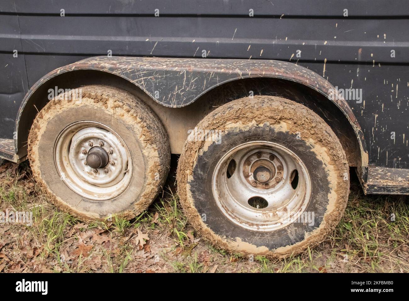 Muddy tires of a cattle or horse trailer sitting on grass with mud ...