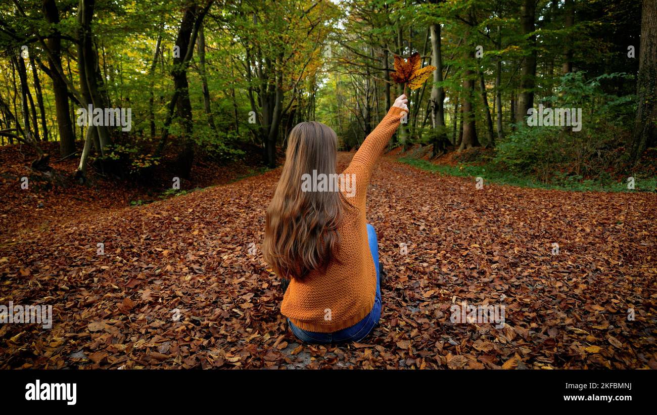The brunette female holding the yellow maple leaf in her hand while ...