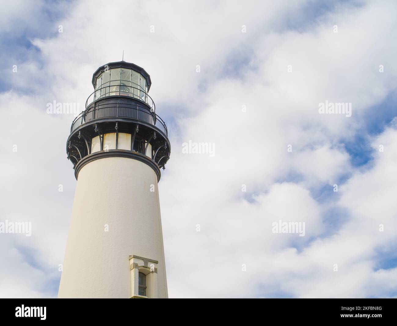 Against the backdrop of a blue sky with white fluffy clouds, a high majestic lighthouse, a high ...