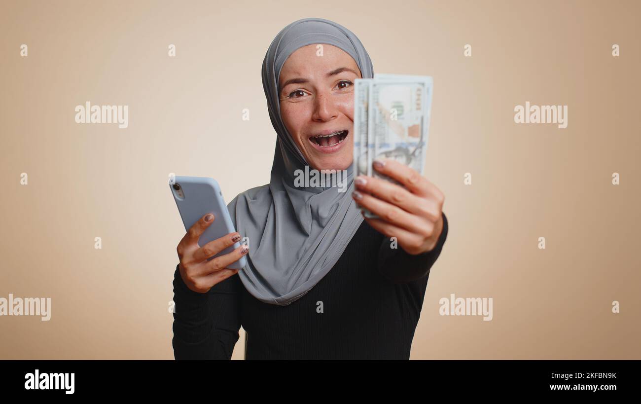 Happy muslim woman in hijab looking smartphone display sincerely ...