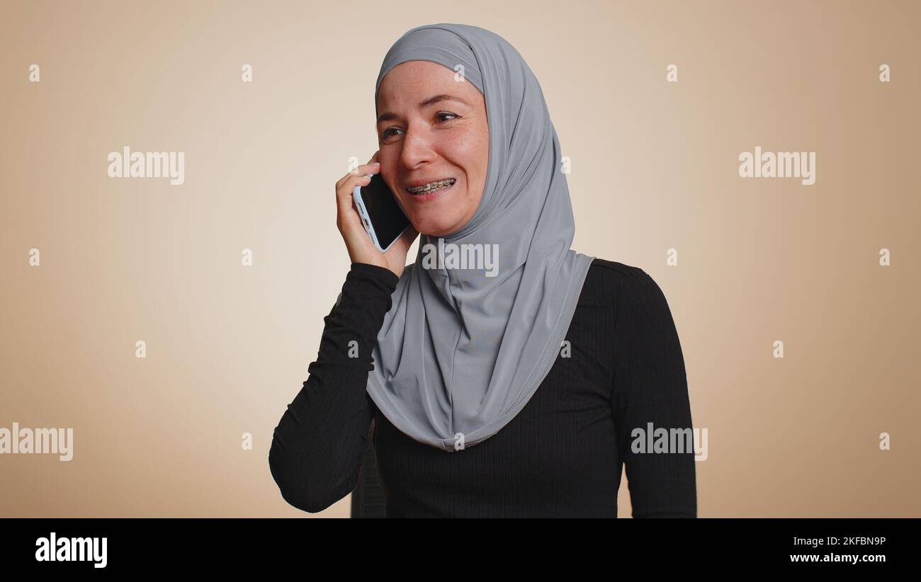 Happy young muslim woman in hijab making call using mobile cell phone ...