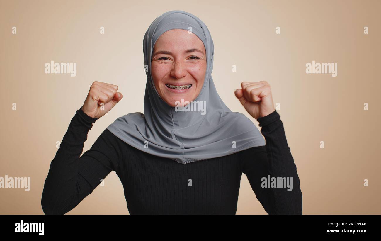 Happy joyful muslim woman in hijab shouting, raising fists in gesture I ...
