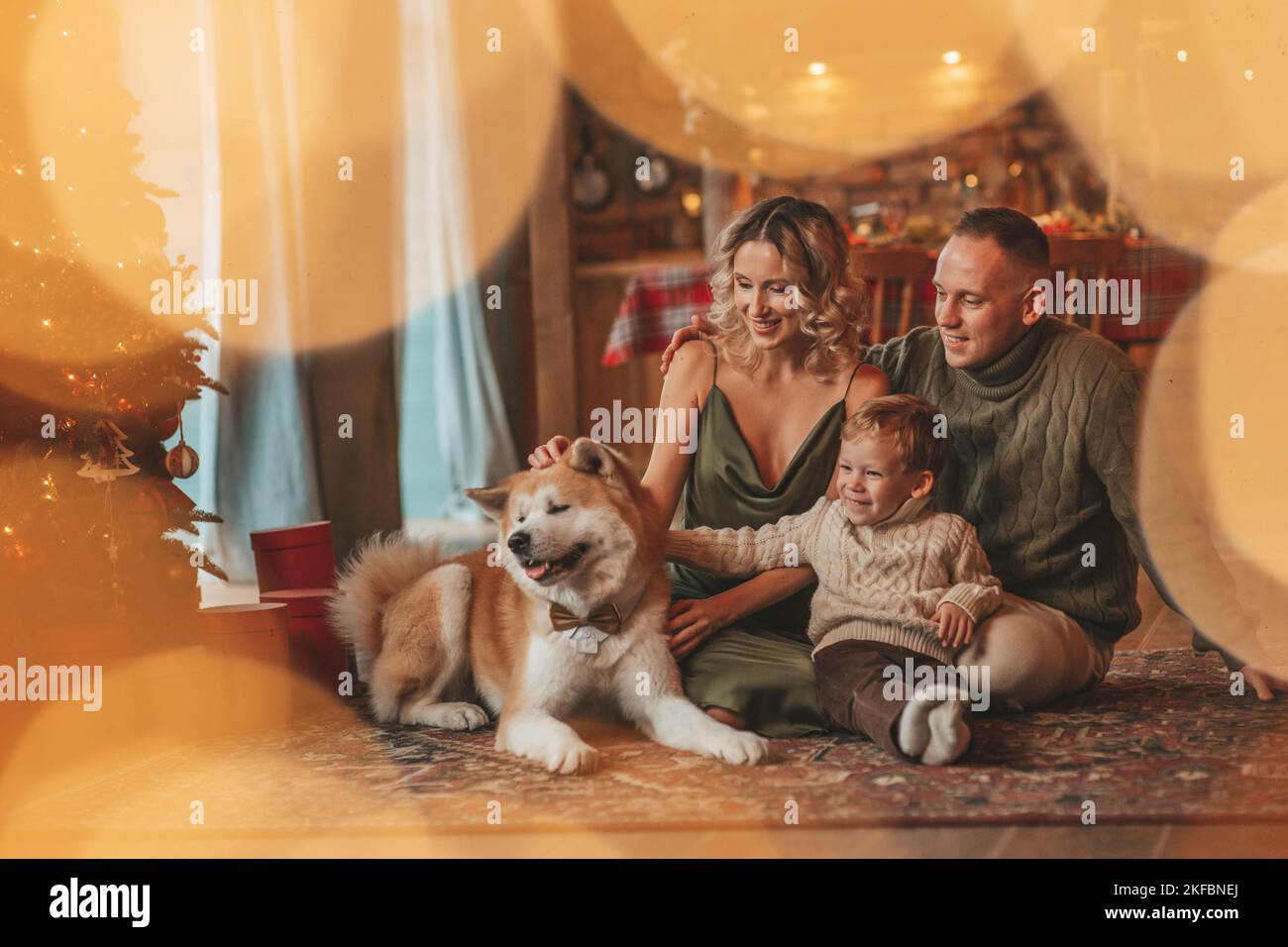 Portrait of happy family in knitted beige sweaters waiting Santa indoor ...