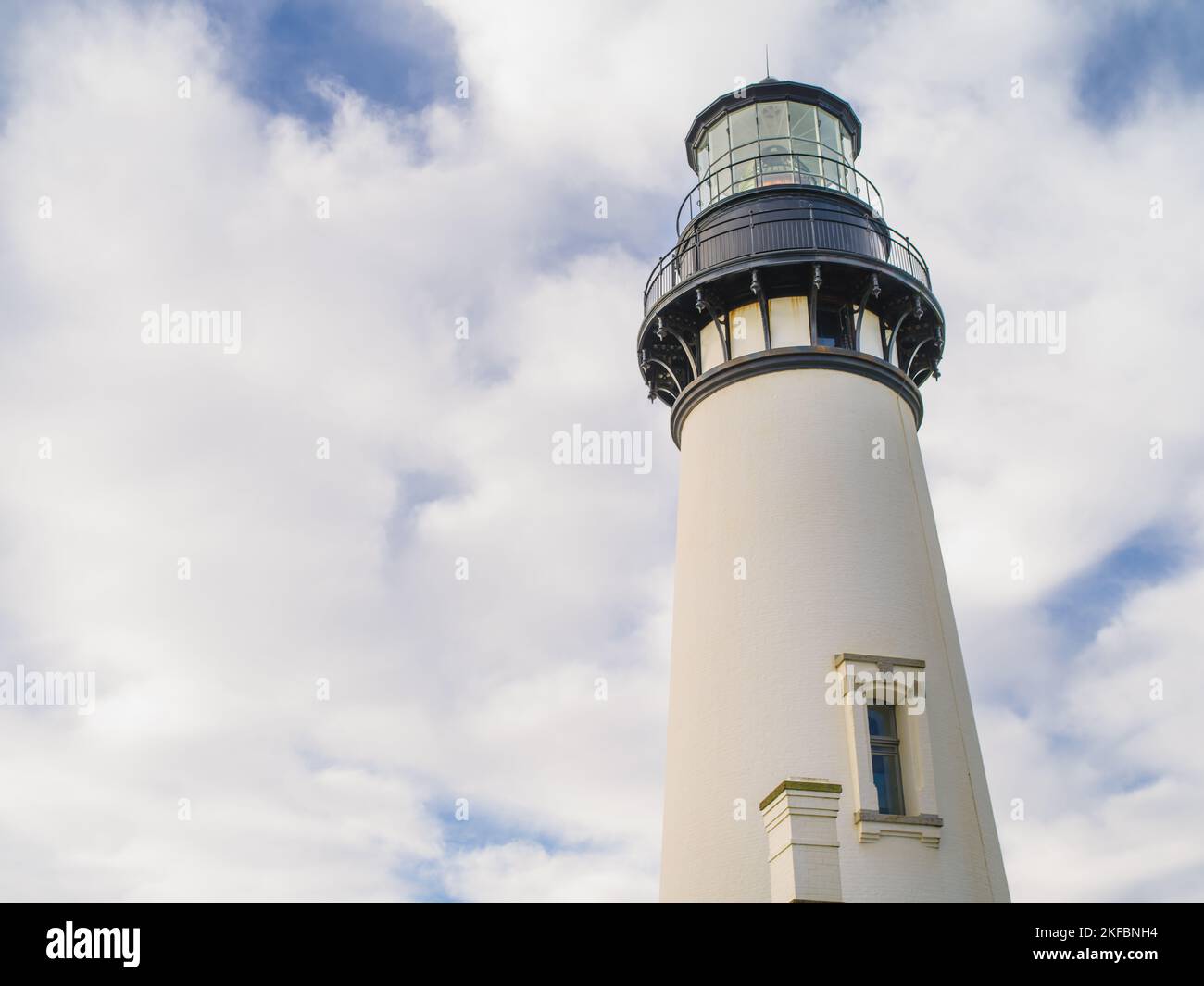 The majestic white lighthouse rests its top on the cloudy sky ...
