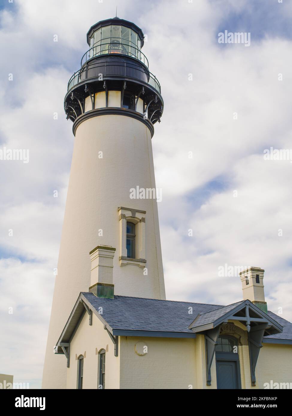 White lighthouse, high tower against the sky with white thunderclouds ...