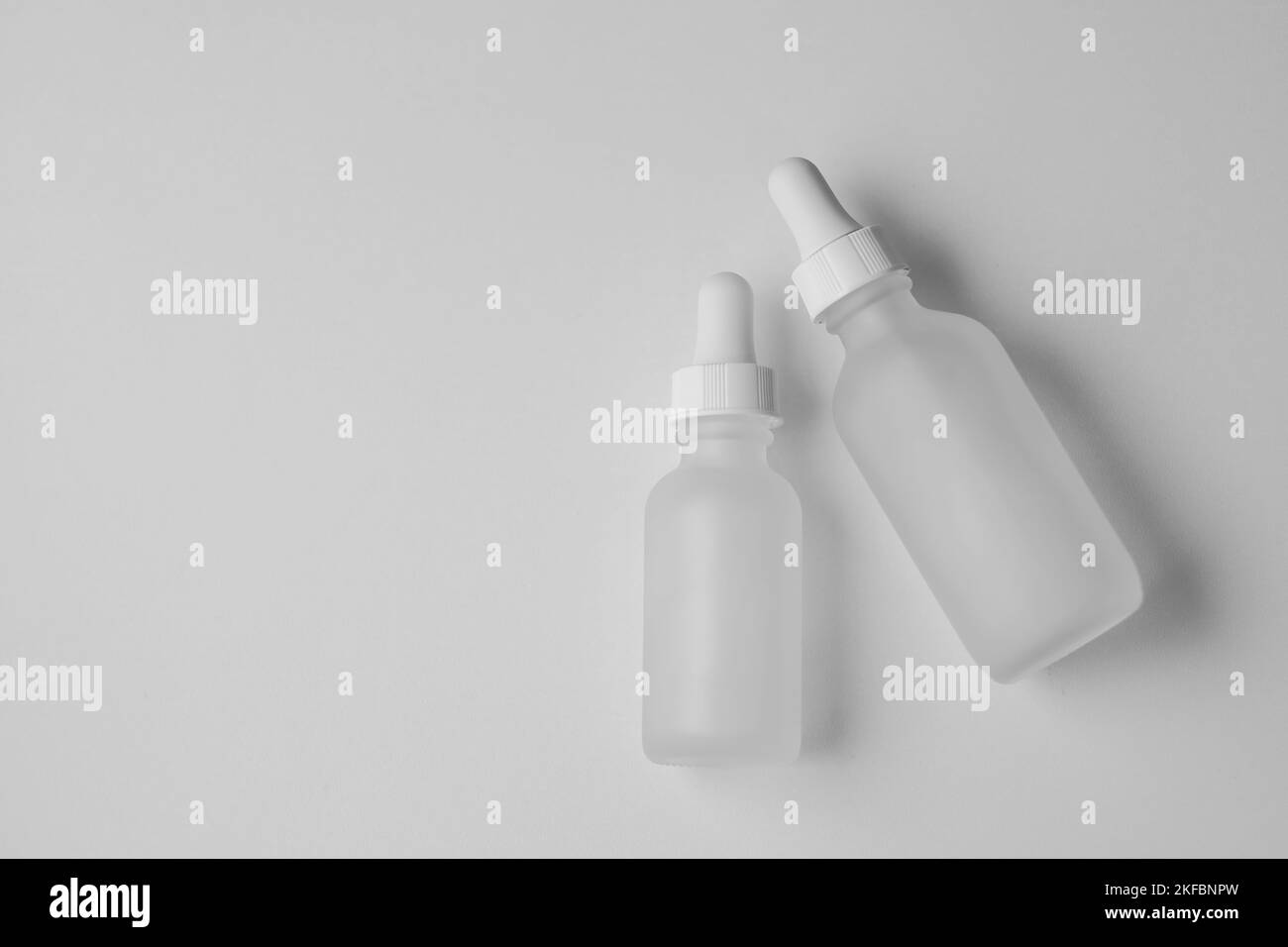 Two empty translucent glass dropper vials. Flatlay of different-sized bottles on white ...