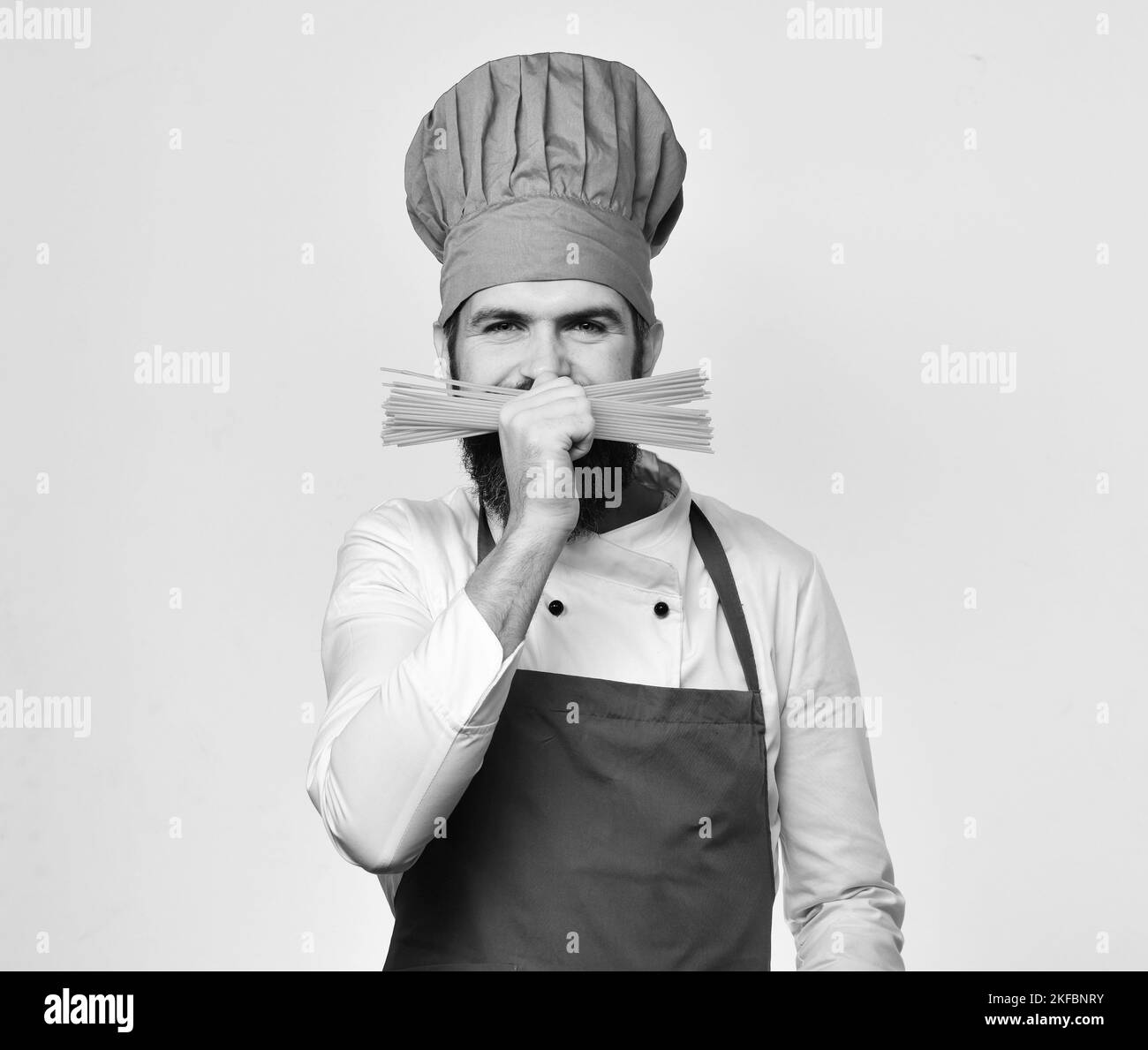 Cook with smiling face in burgundy uniform holds dry pasta Stock Photo ...