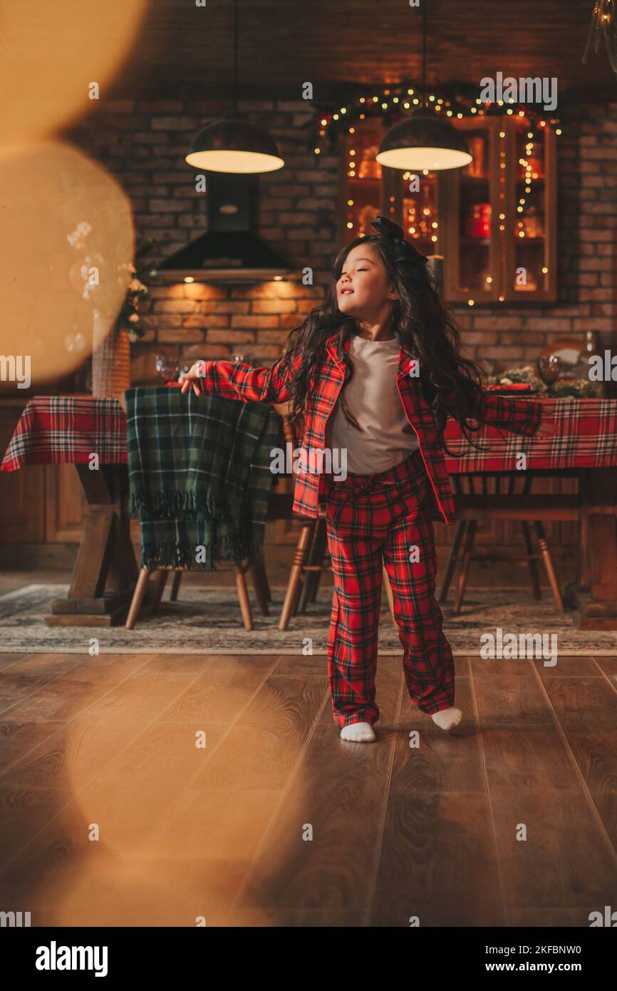 Active japan kid girl with stylish long brunette hair model pose at home in bokeh garlands noel ...