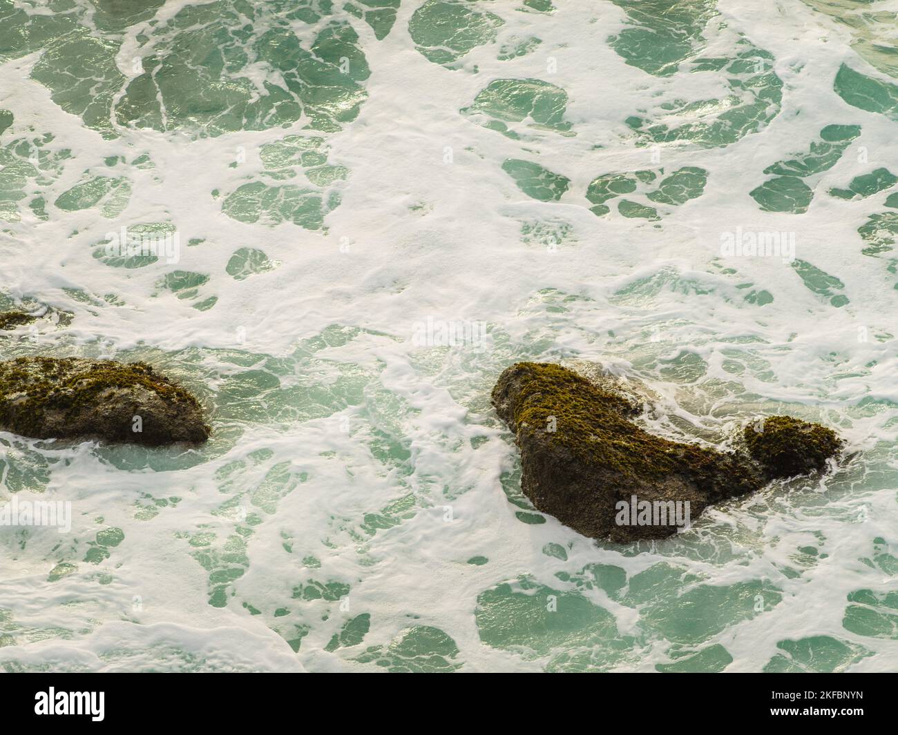 Storm in the ocean. White foamy waves are beating against large stones ...