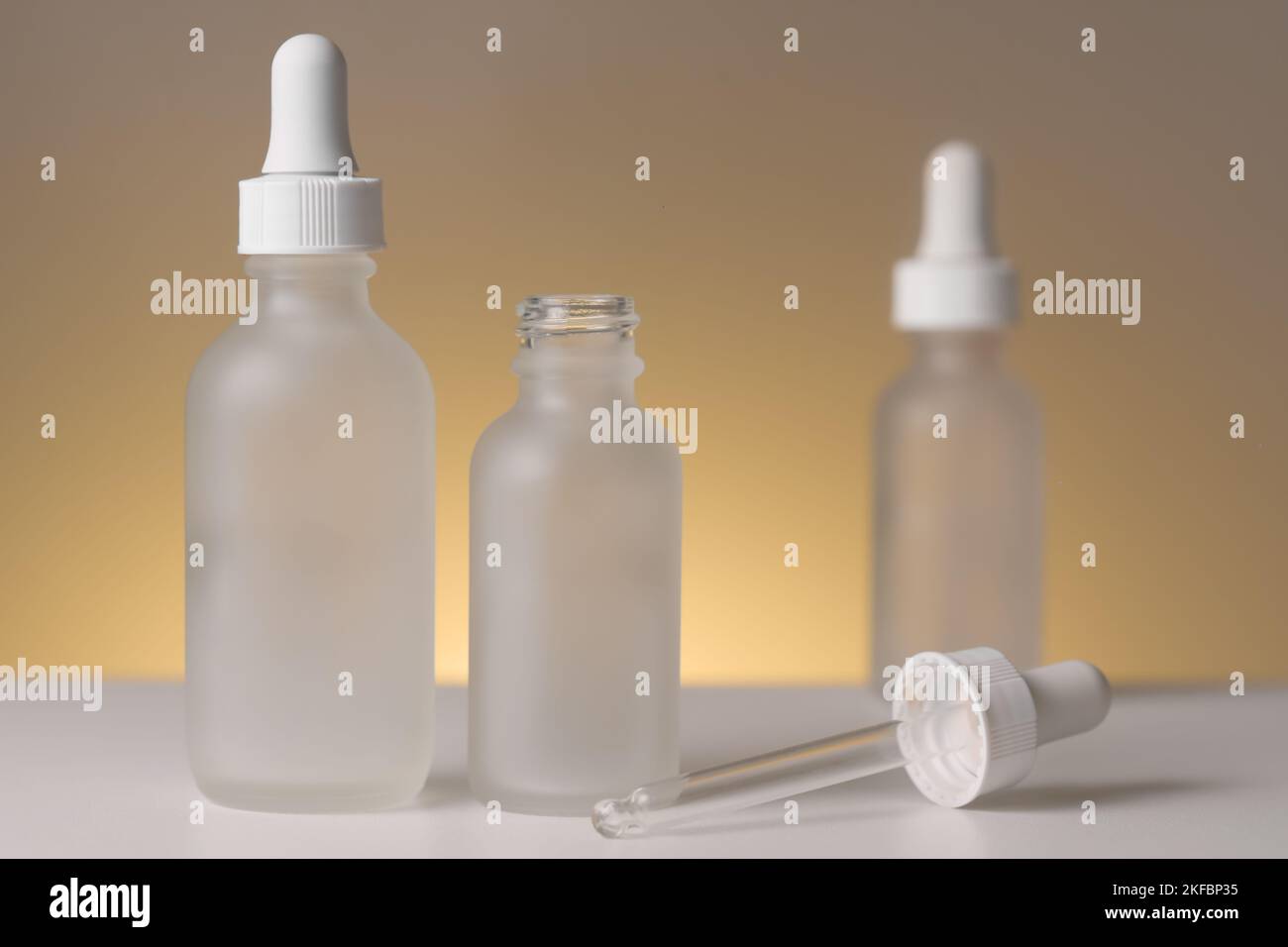 Three empty translucent glass dropper vials, one open, one blurry. Different-sized bottles on ...