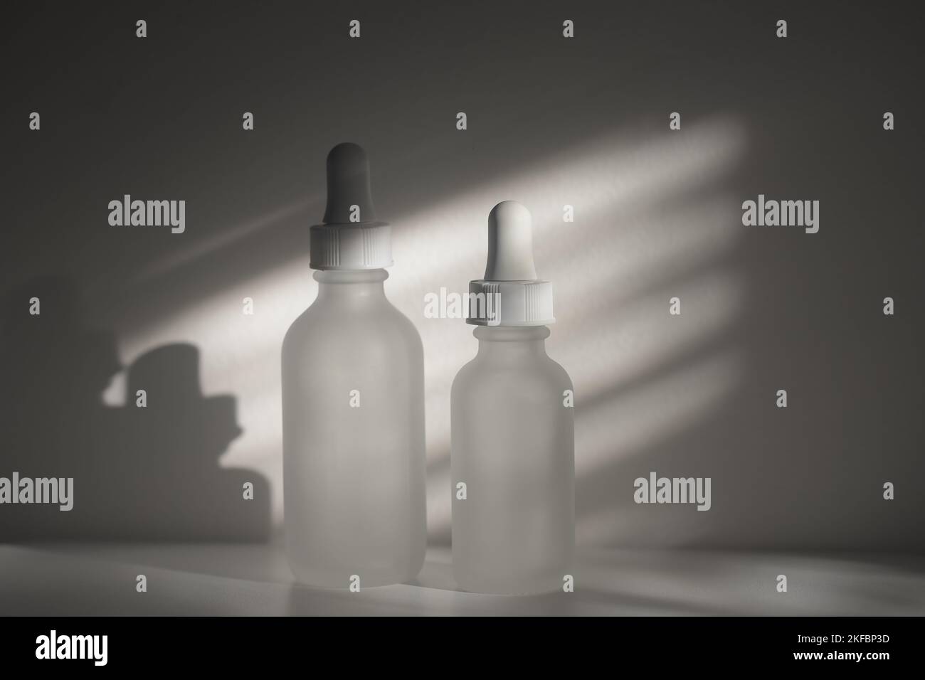 Two empty translucent glass dropper vials. Different-sized bottles on white background with ...