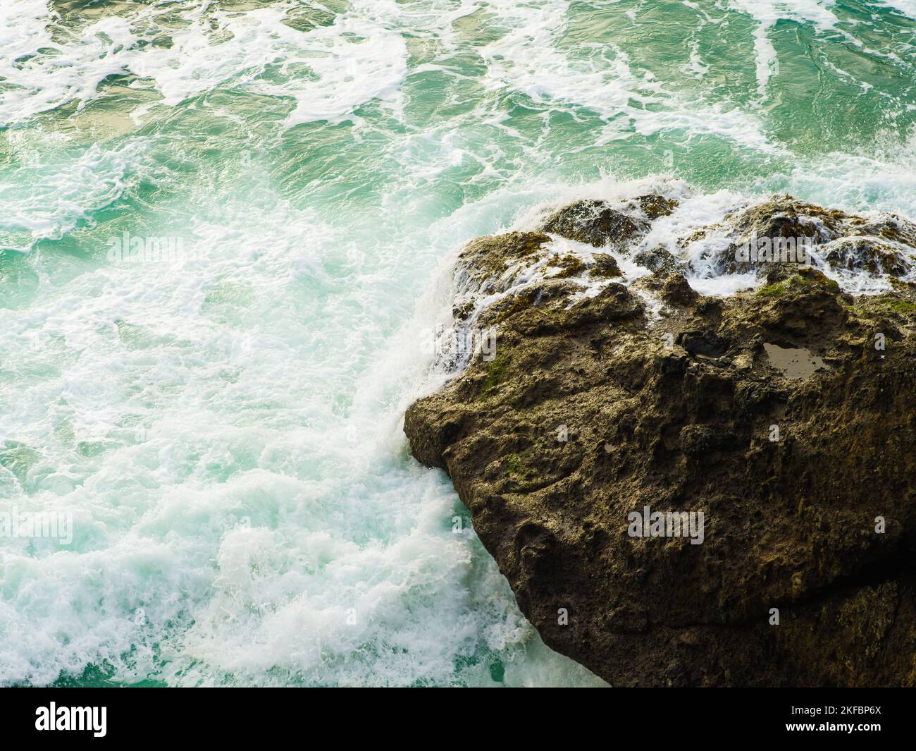 Seascape. Big boulder in the ocean. Foamy waves crash against the stone ...