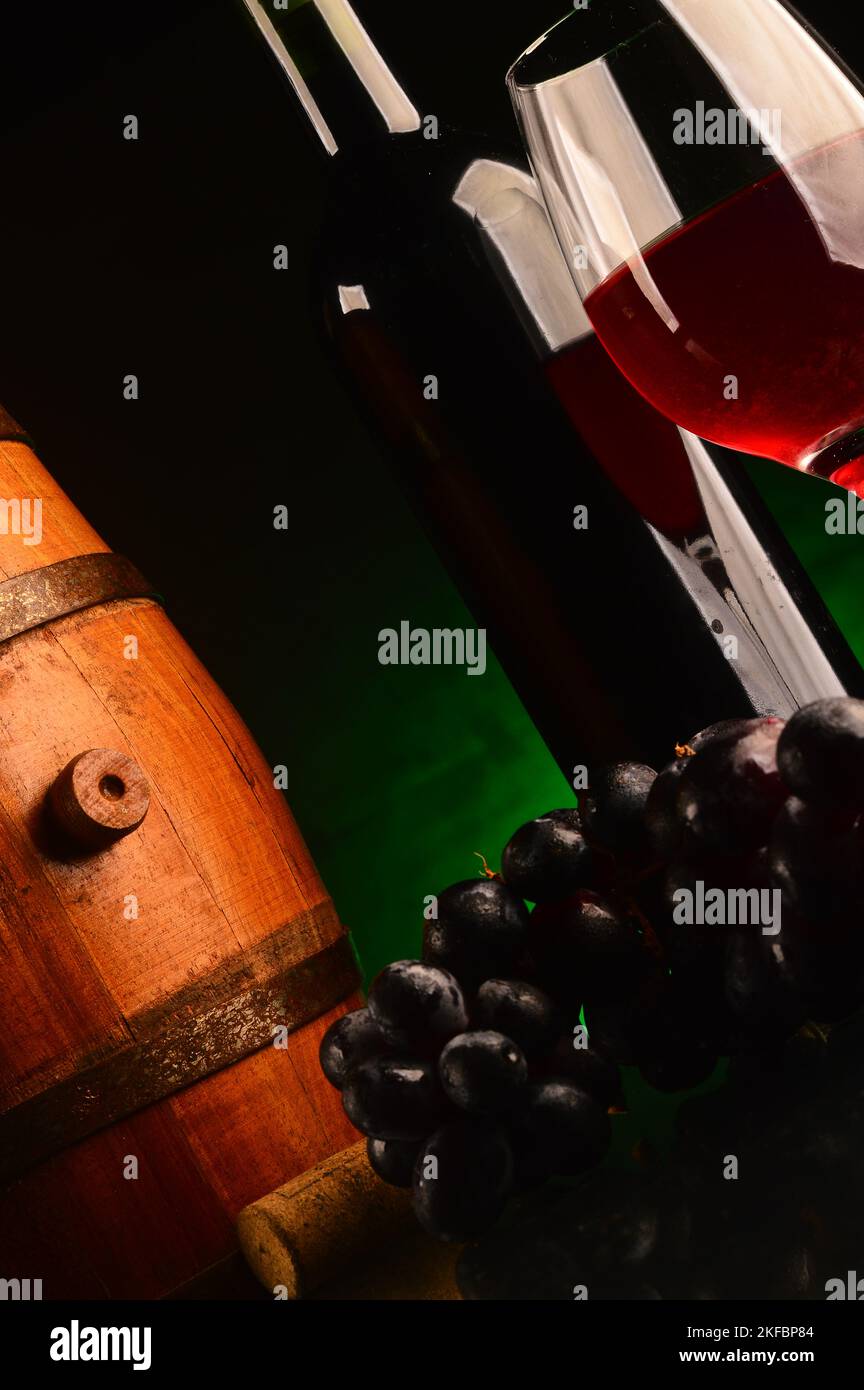 still life with wine barrel, grape, bottle and glass dark green ...
