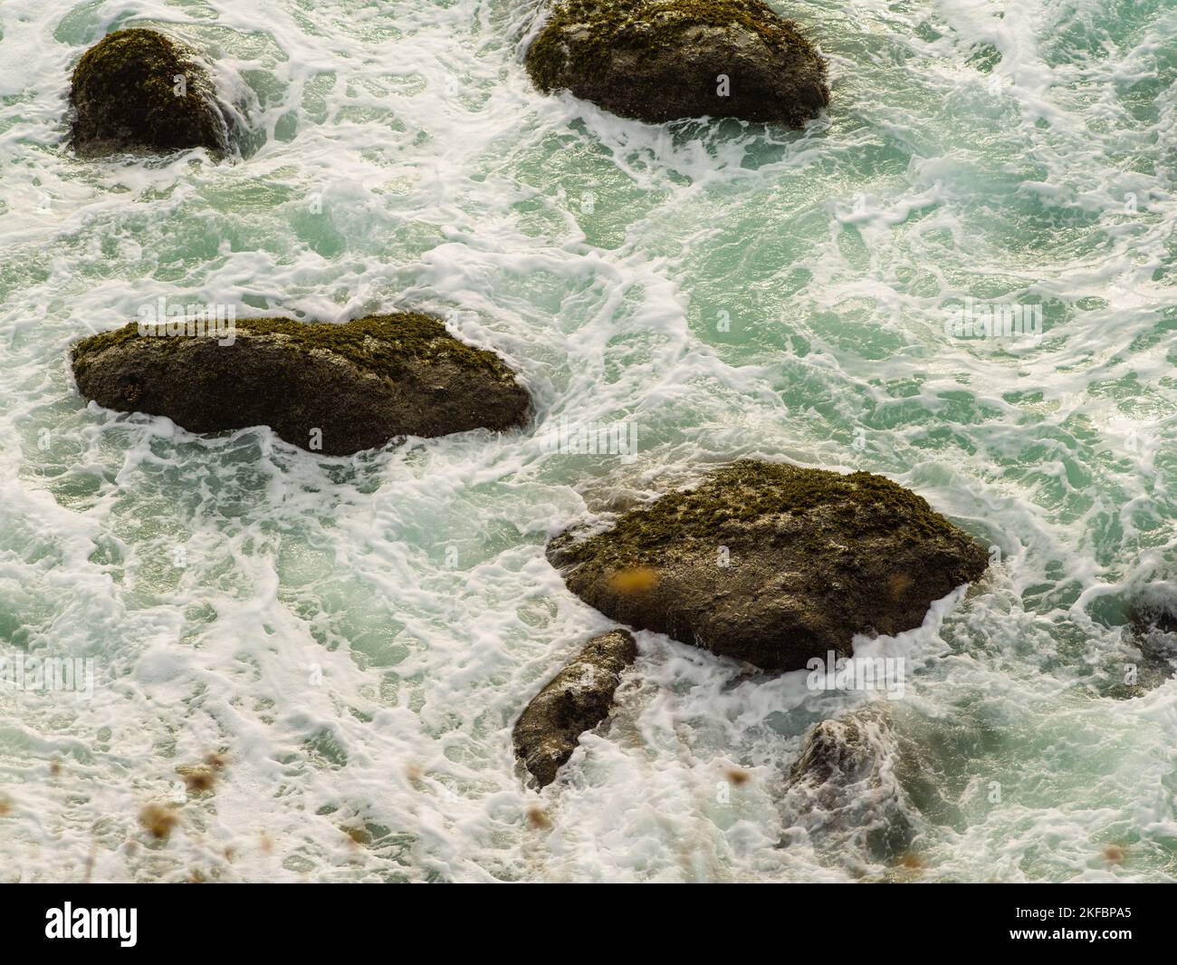 Stones, boulders in the ocean. White foamy waves wash the stones from ...