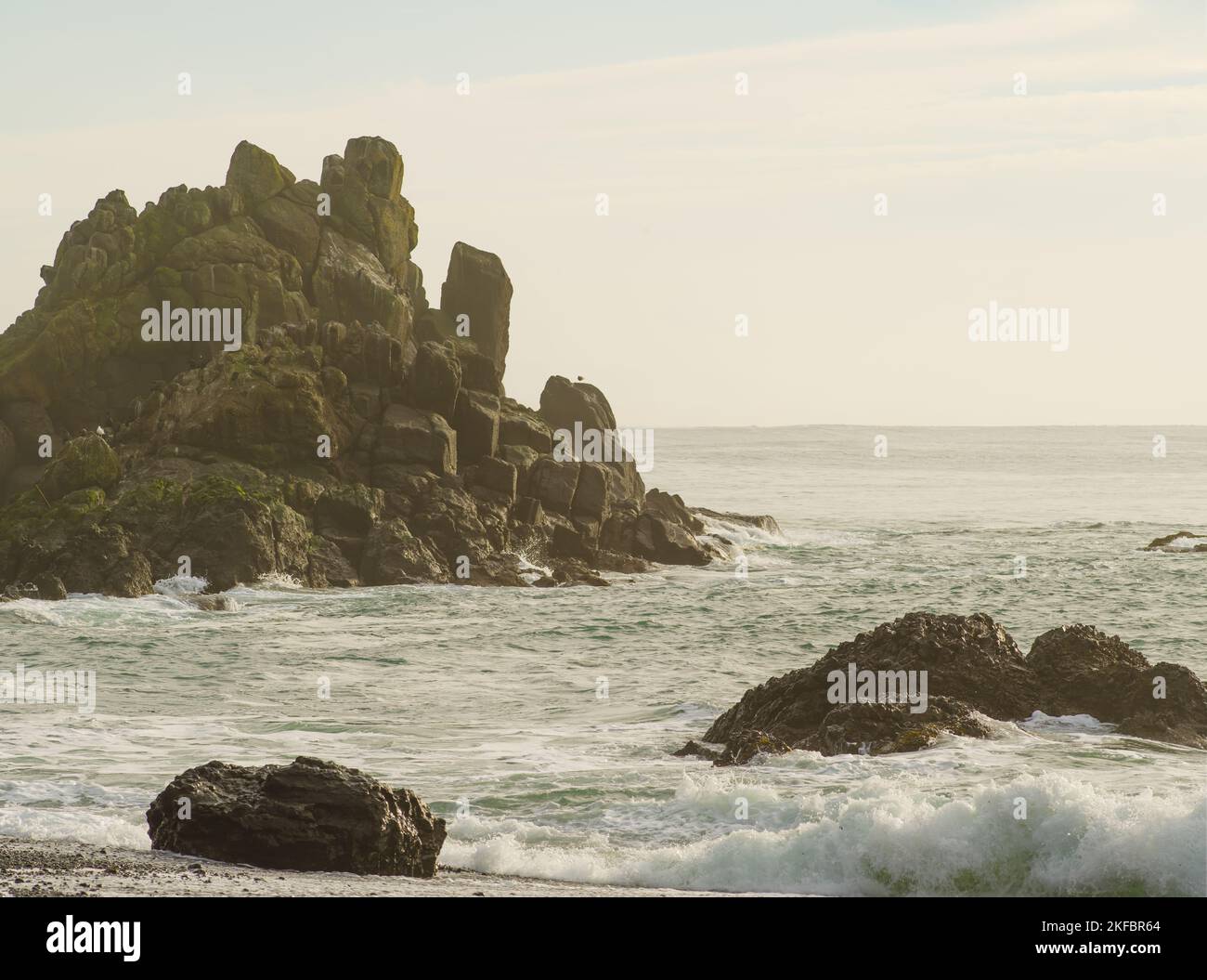 Big rock and boulders in the ocean. White foamy waves. Dramatic sky ...