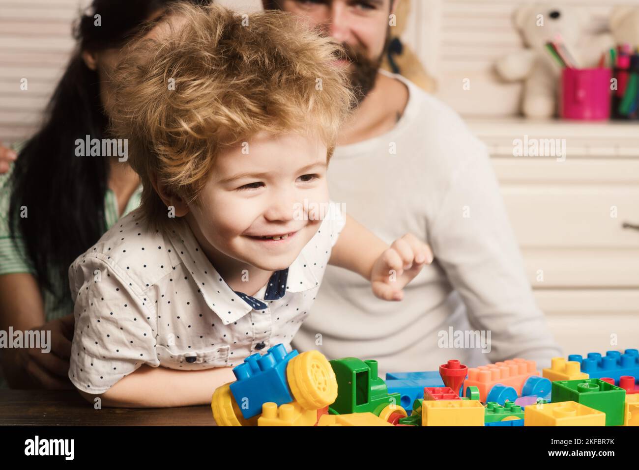 Parents watch their son play with colorful blocks Stock Photo - Alamy