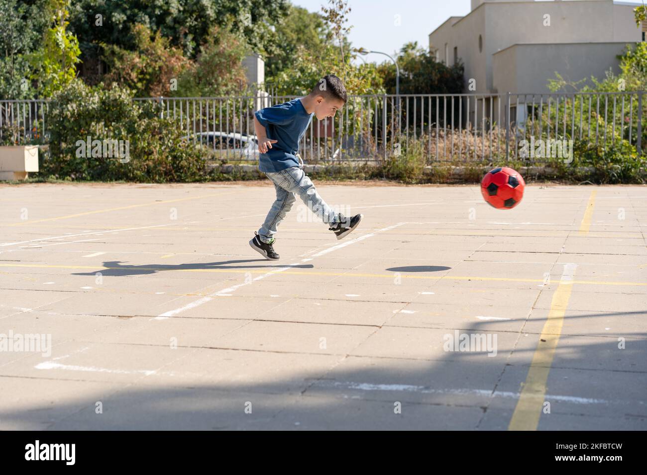 Little Child Kicking Soccer Ball. Cute Boy Running With Ball On Street ...