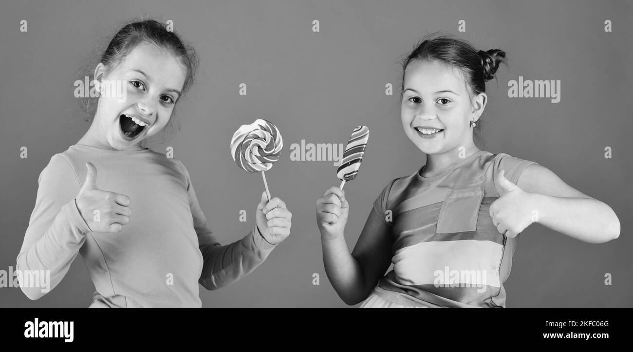 Children eat big colorful sweet caramels. Sisters with lollipops Stock ...