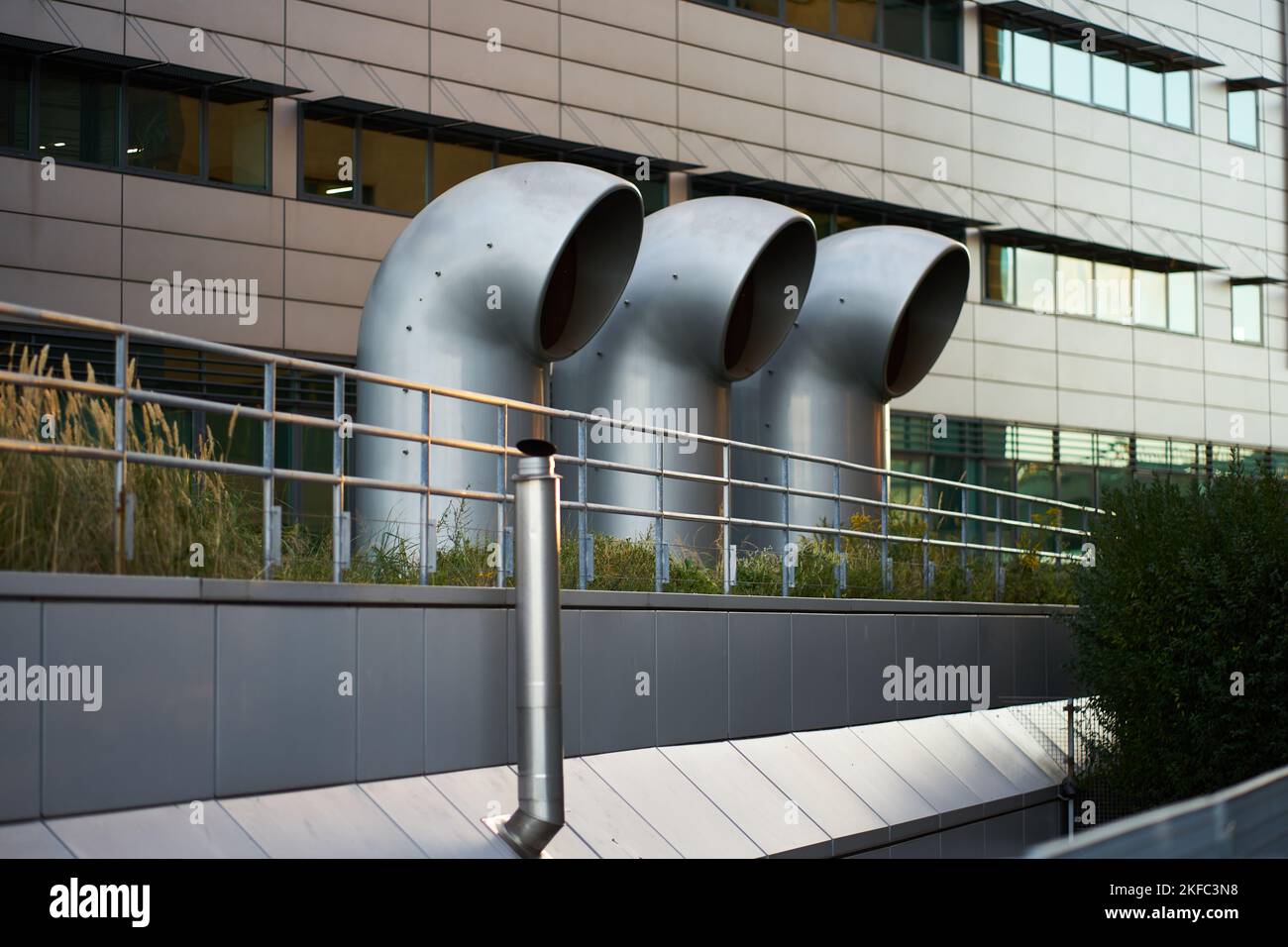A close-up shot of massive ventilation pipes against a modern office ...