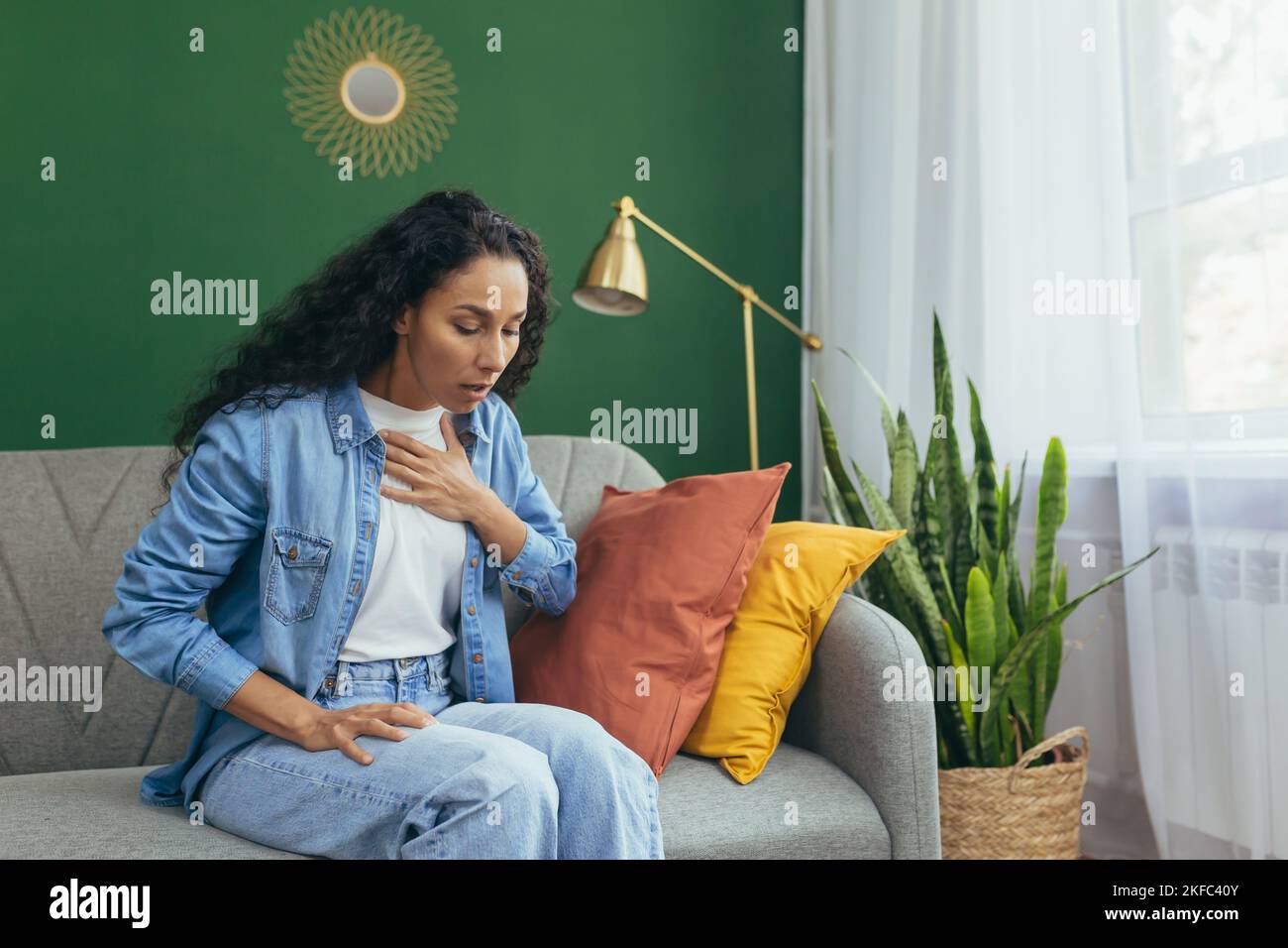 Panic attack. A young beautiful Latin American woman is sitting at home ...