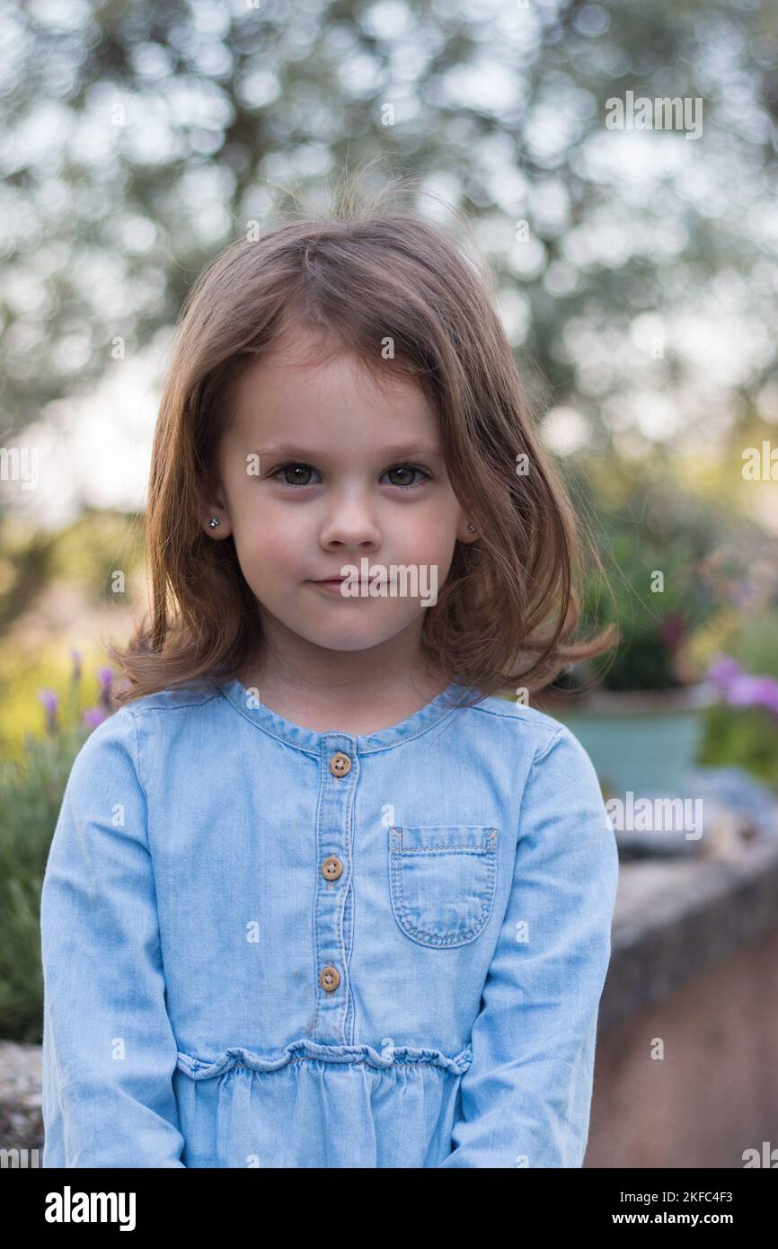 A little beautiful preschooler girl stands in a denim blue dress ...