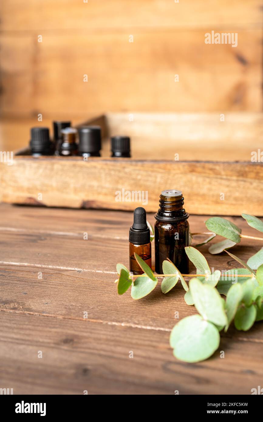 Essential oils in small glass bottles with eucalyptus sprigs on a wood ...