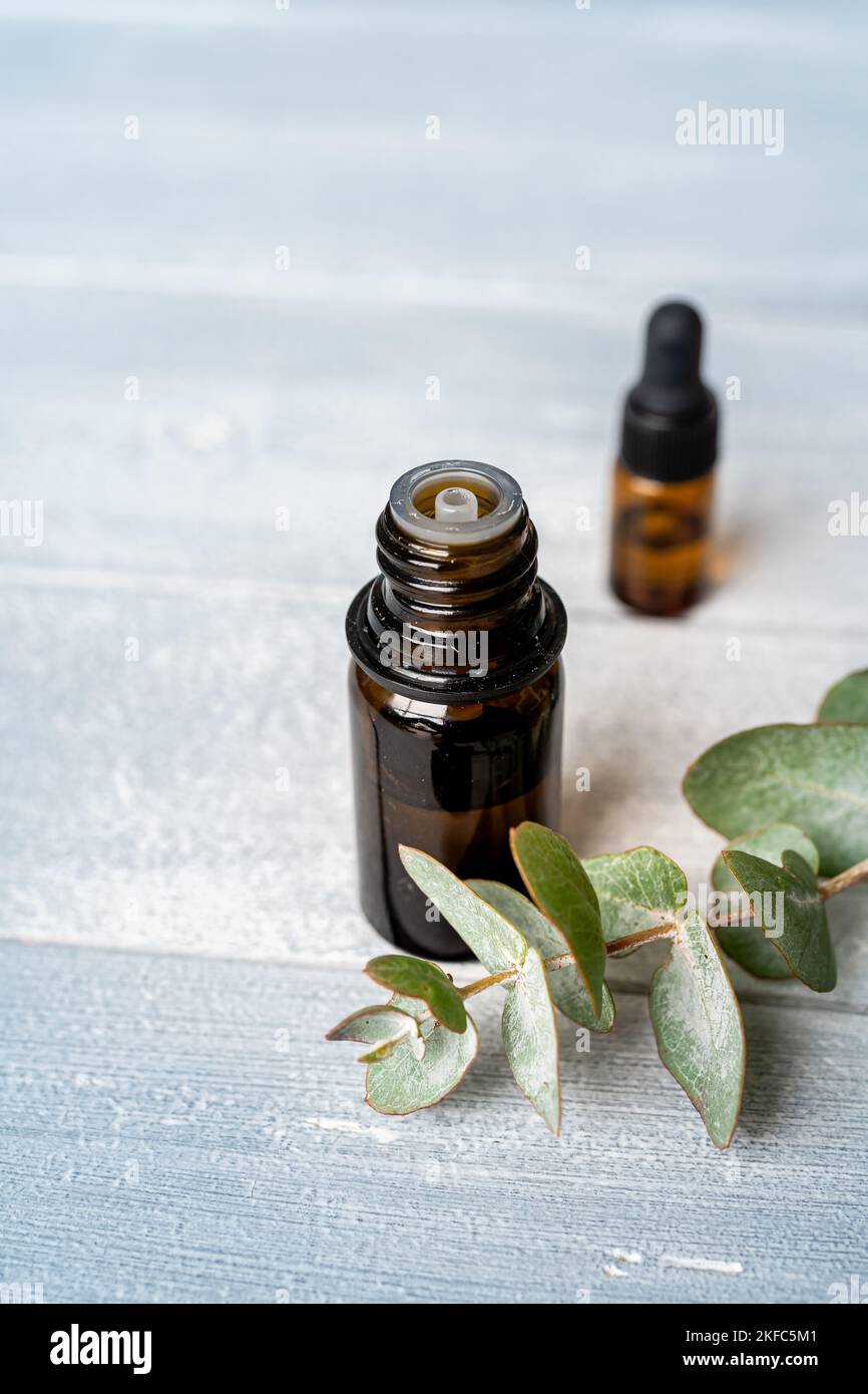 Essential oils in small glass vials with eucalyptus sprigs on a wood ...