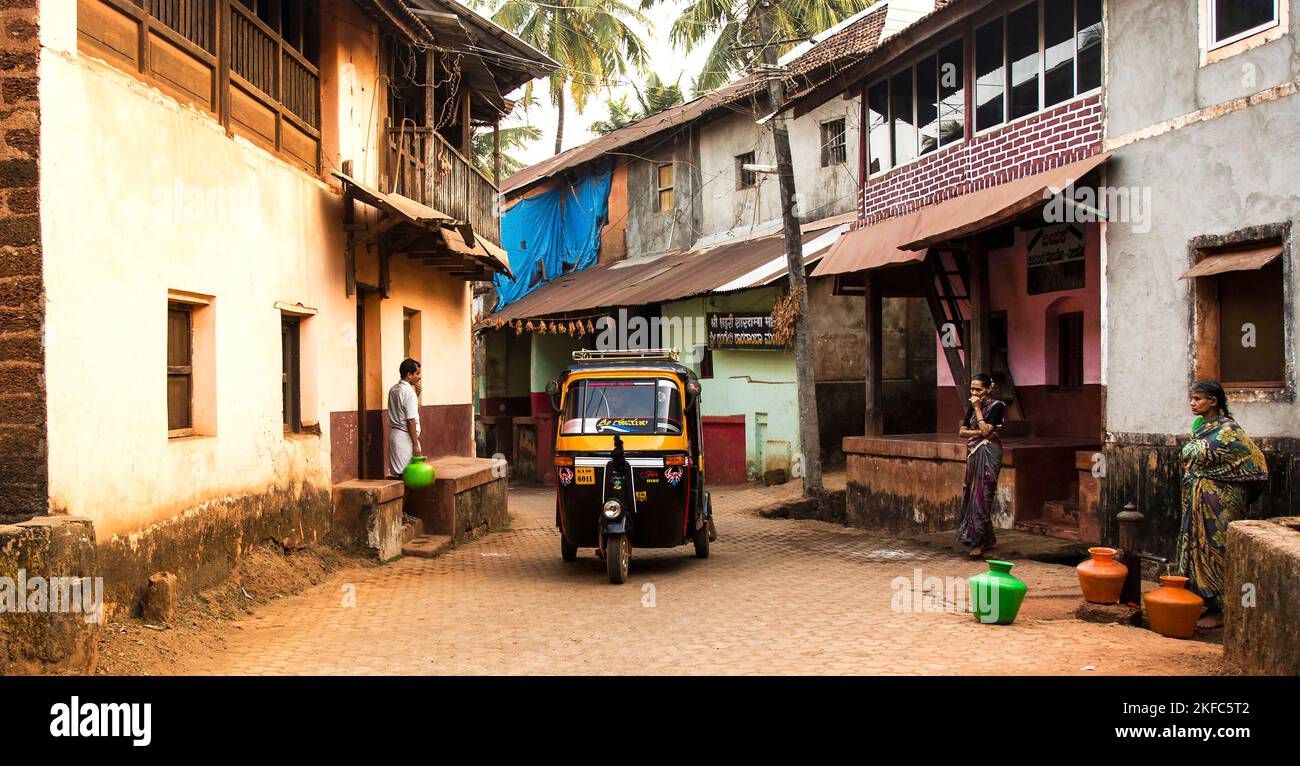 The urban view of the yellow rickshaw and local people with jugs of ...