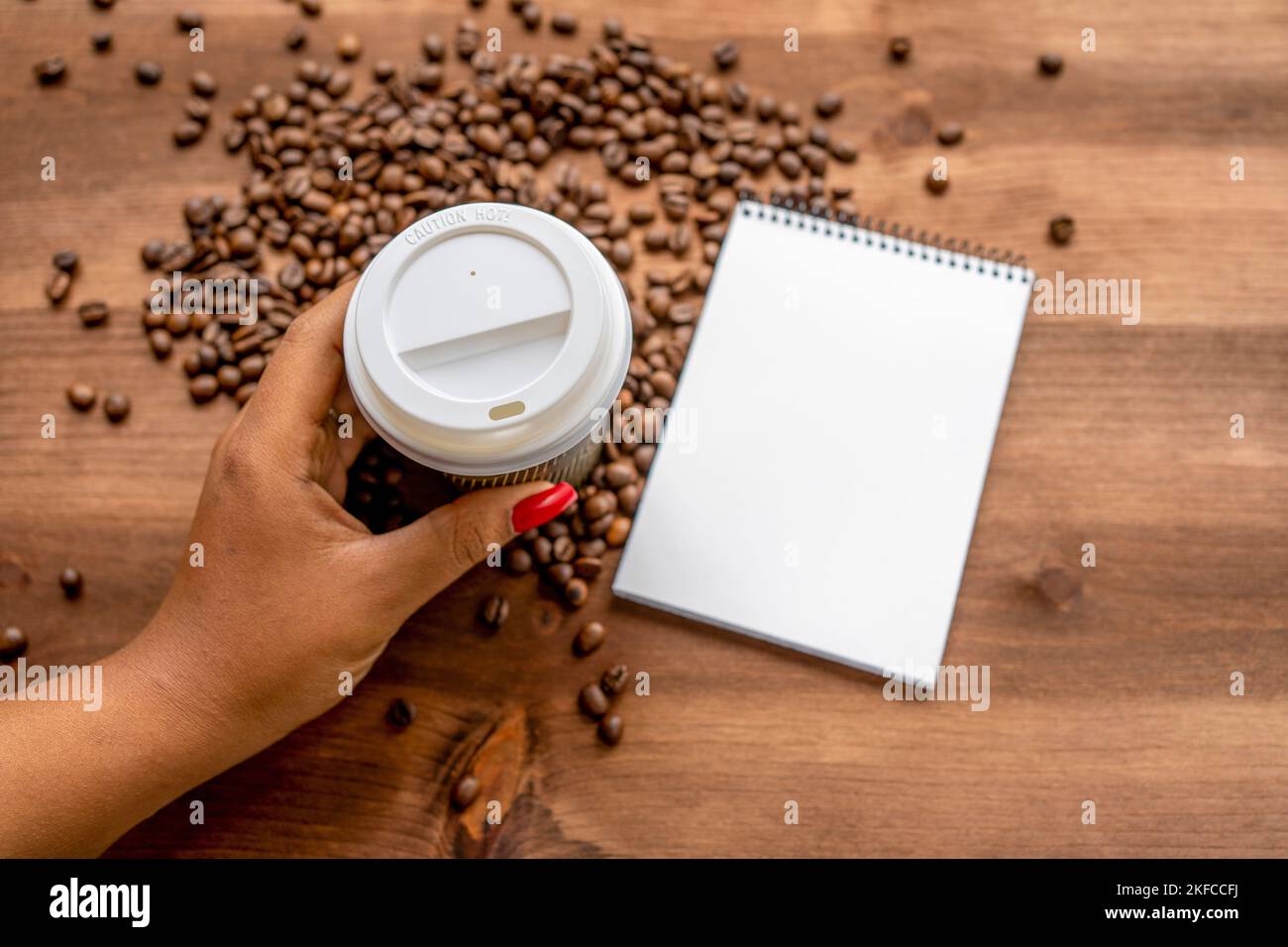 woman's hand holding a cup of take-away coffee on a rustic wooden table ...