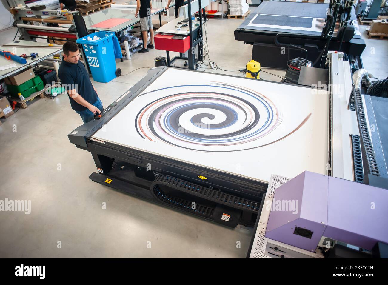 In the printing house, an experienced technician works on a UV printer ...