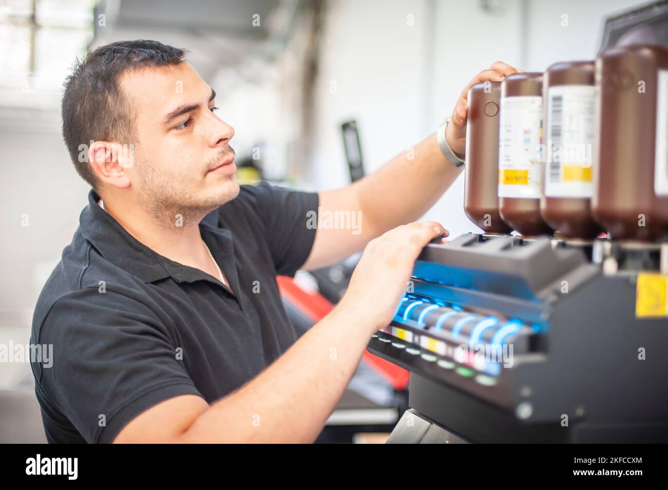 In the printing house, an experienced technician works on a UV printer ...