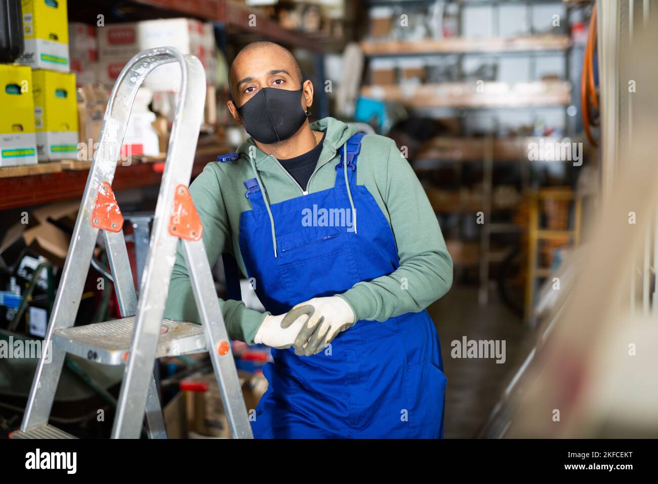 Workman in protective mask standing among shelving in construction ...