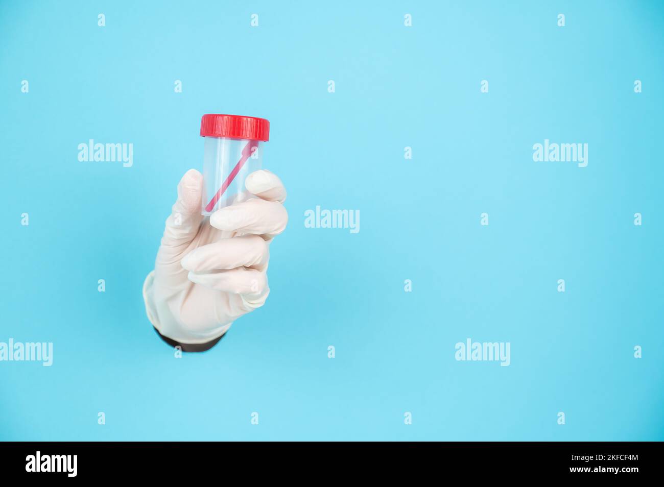 A woman's hand in a rubber glove sticks out through a blue paper ...