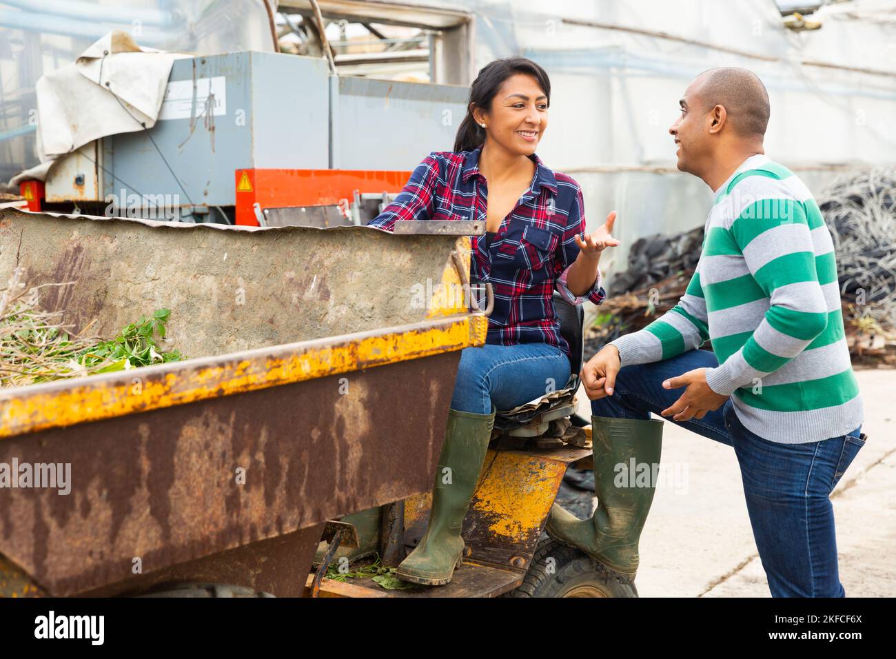 Latin american woman farmer driving a mini dump truck, communicates ...