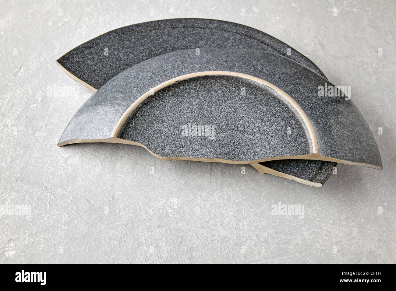 Two halves of a cracked ceramic plate on a gray concrete table Stock ...