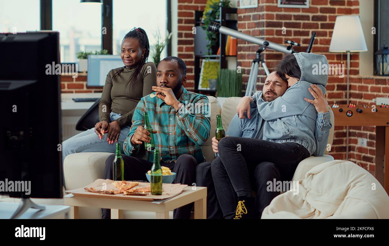 Multiethnic group of people getting scared watching horror film ...