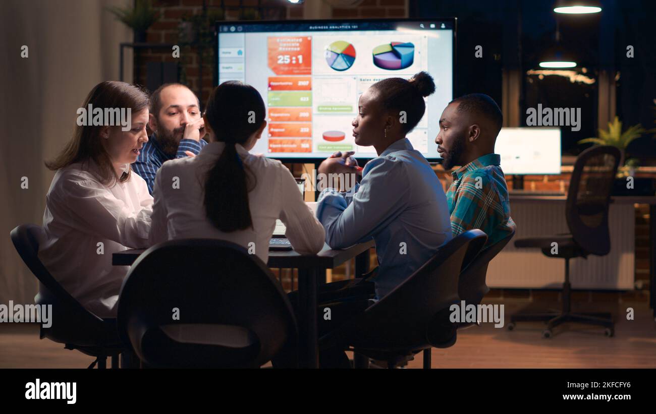 Diverse coworkers brainstorming in business meeting, discussing analytics presentation ...